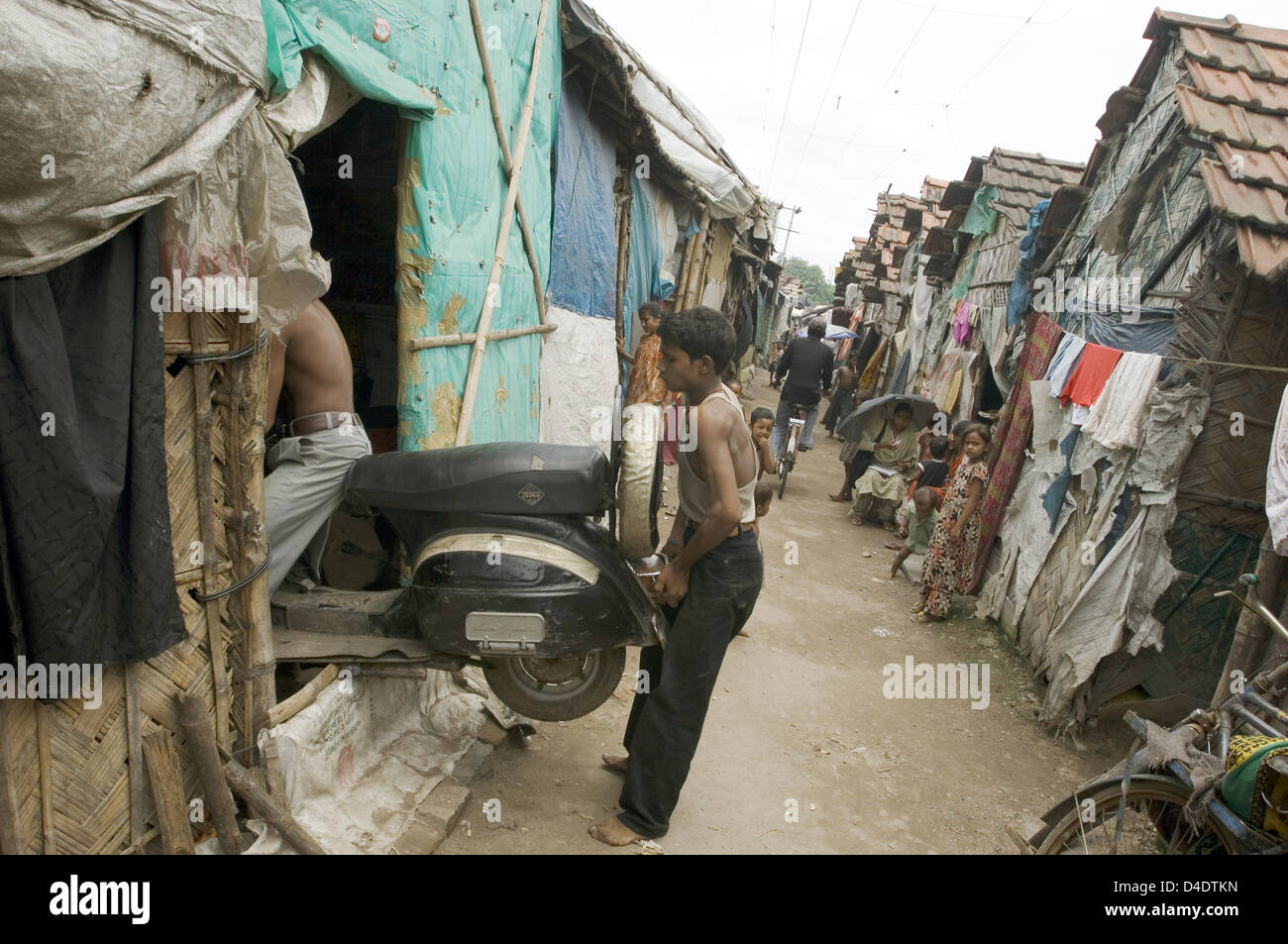 Two boys carry a motor scooter into their hut located in the slum of ...