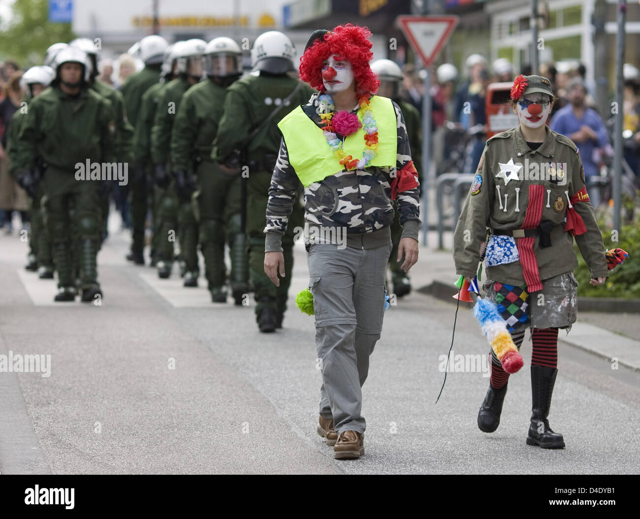 Two left-wing demonstrators dressed as clowns walk in front of a group ...