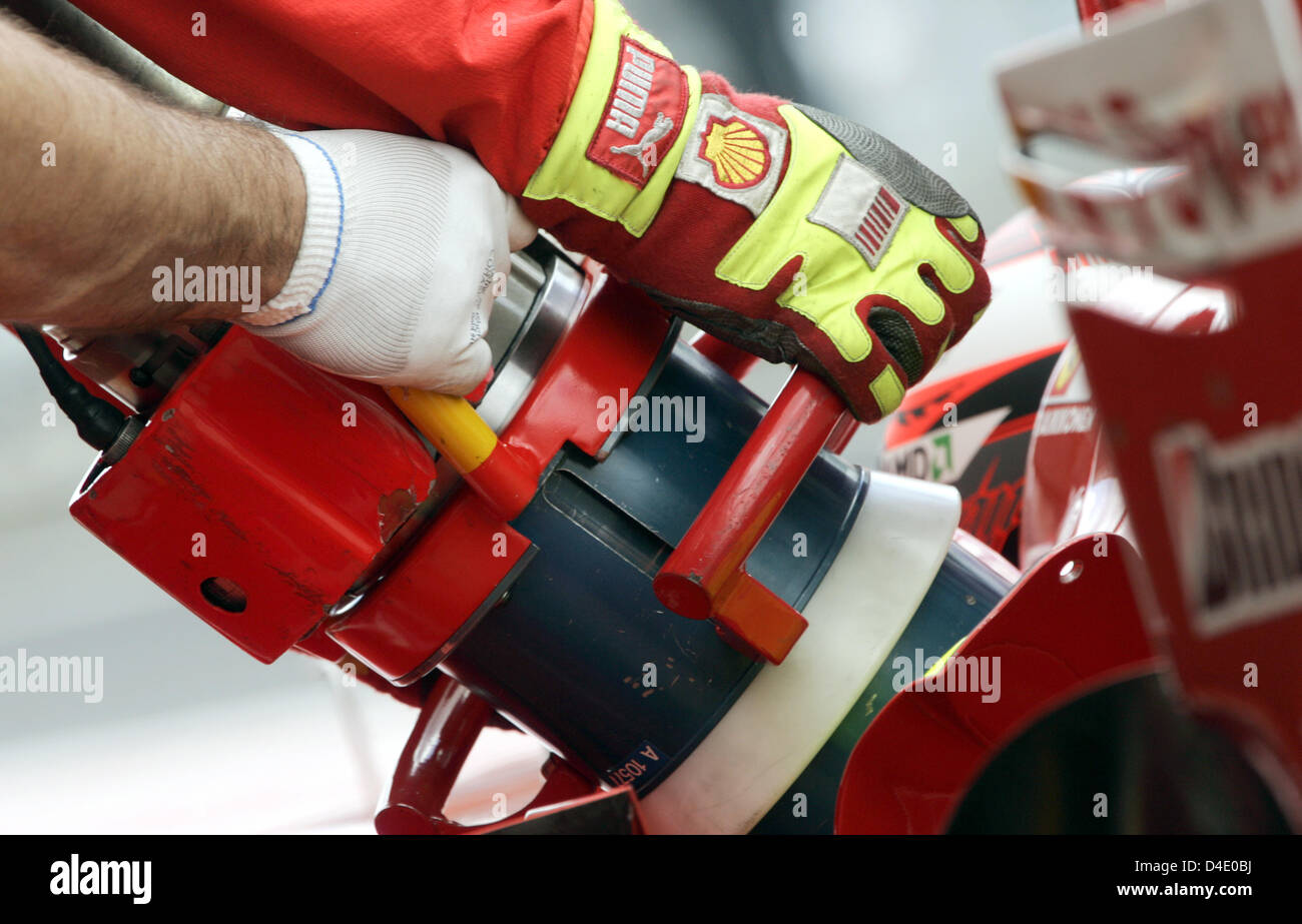Mechanics of Scuderia Ferrari pump fuel into the racing car of Finnish ...
