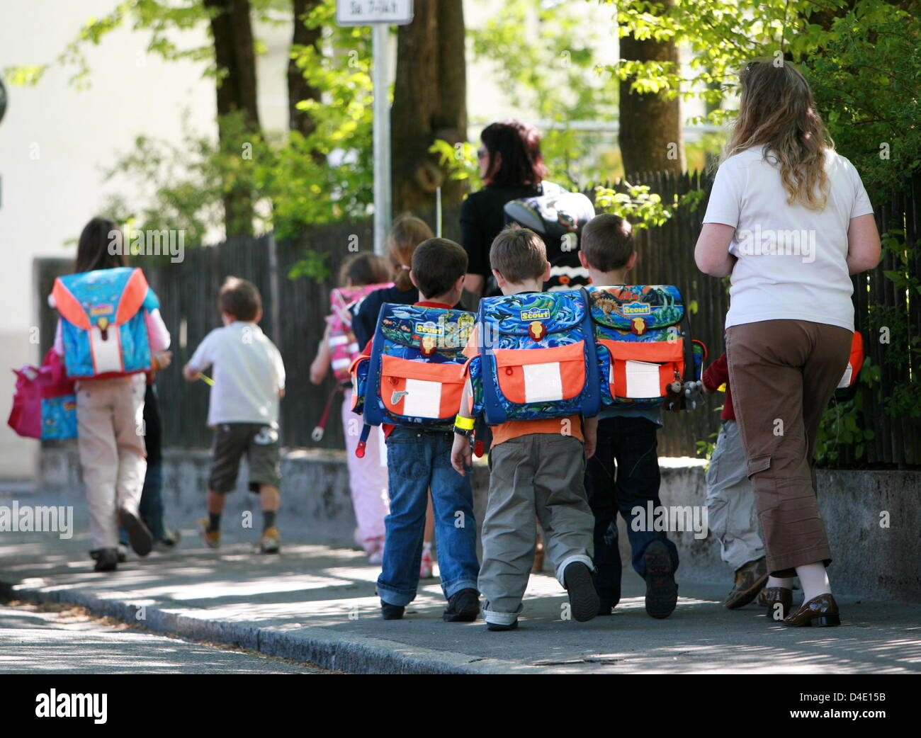 A group of pupils with knapsacks on their backs is accompanied by two ...
