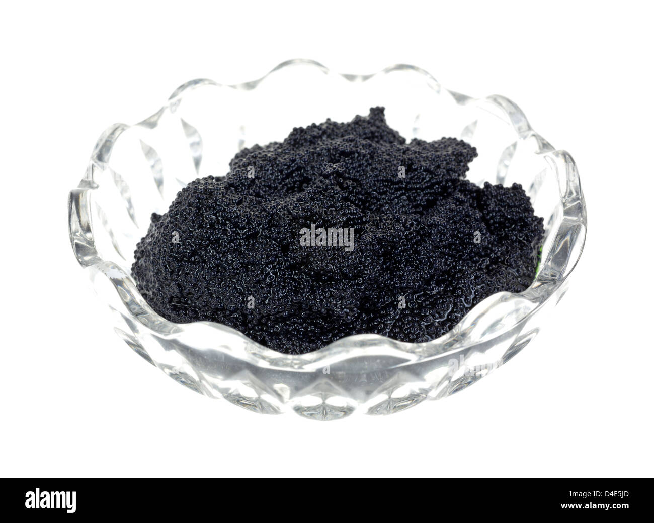 A small ornate glass bowl filled with black caviar on a white ...