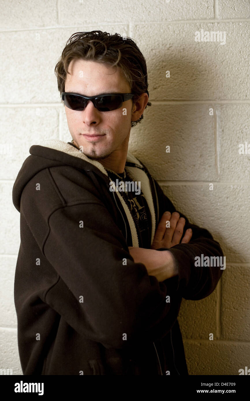 Young man leaning against a cinder block wall Stock Photo - Alamy
