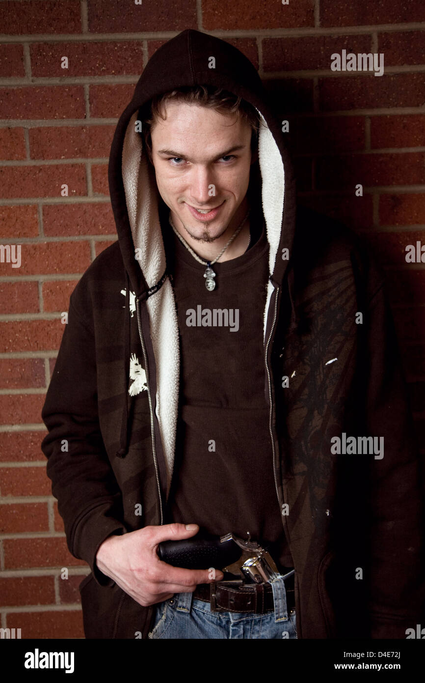 Young dangerous looking man with a firearm wearing a hoodie Stock Photo ...