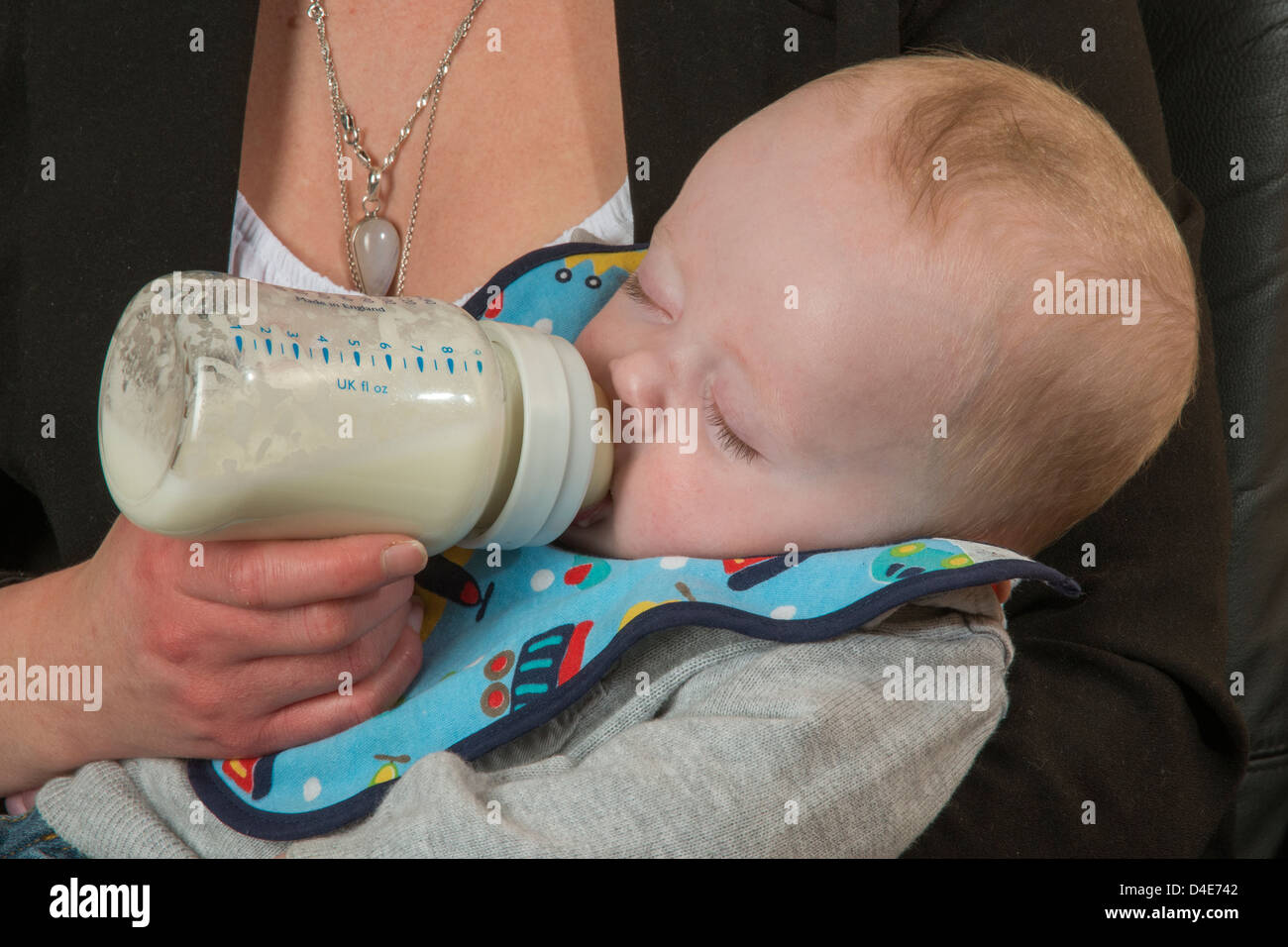 Baby boy being bottle fed by his young mother Six month old child Stock ...