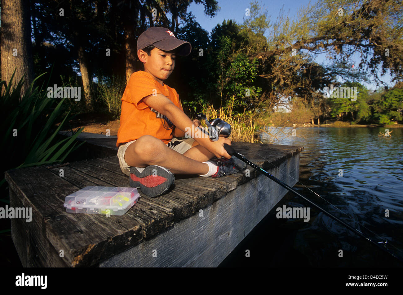 Young boy fishing from a dock on a small pond Stock Photo - Alamy
