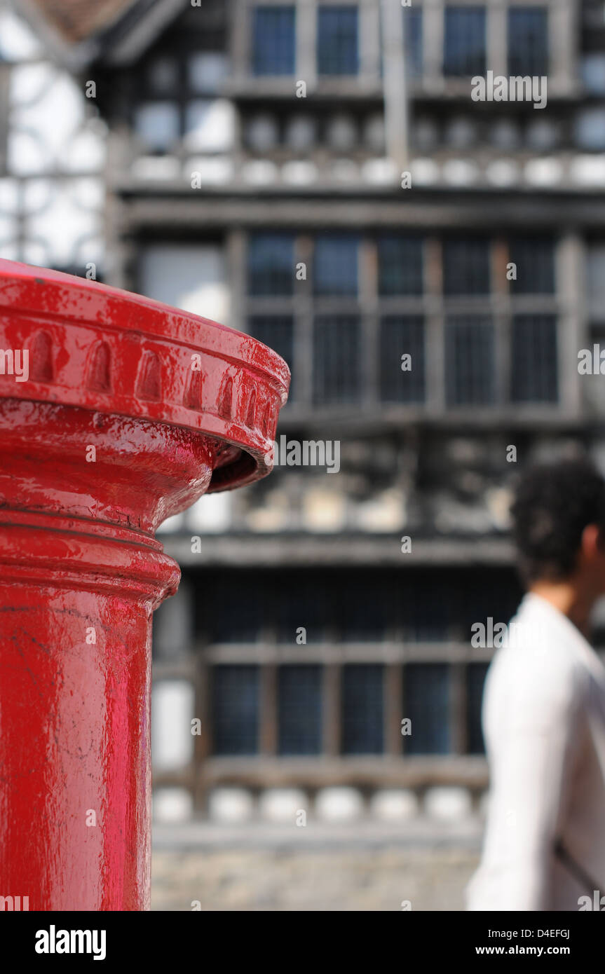 A traditional bright red English post box with a back-drop of an ...