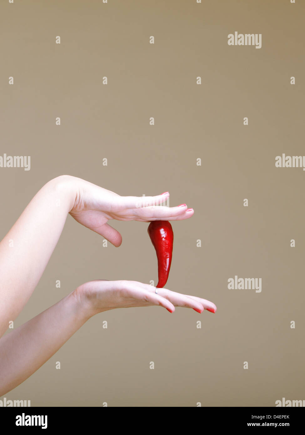 chili pepper in female hand brown background Stock Photo - Alamy
