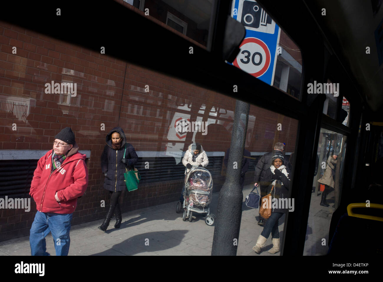 Bus passengers and city travellers are seen through a bus window as ...