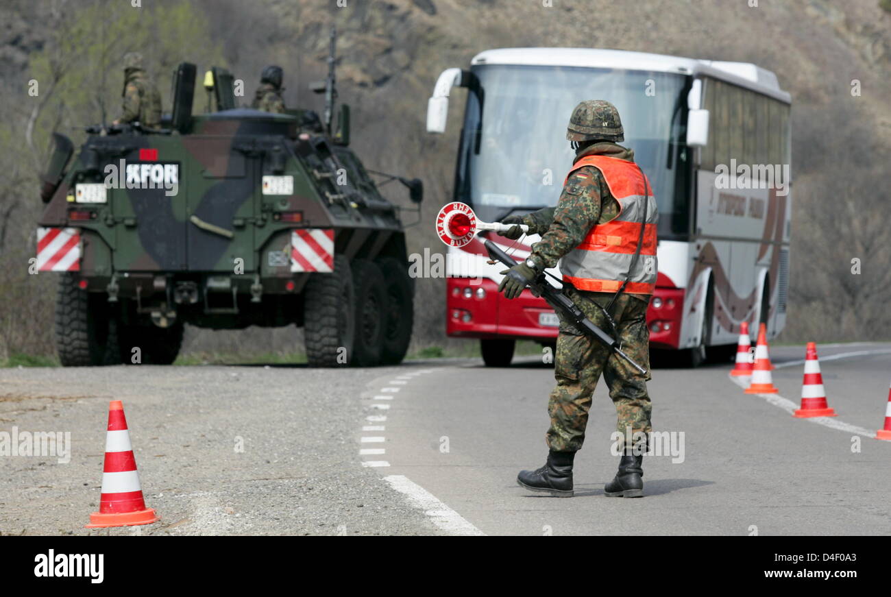 An armed solder of German Bundeswehr directs a bus during a street ...