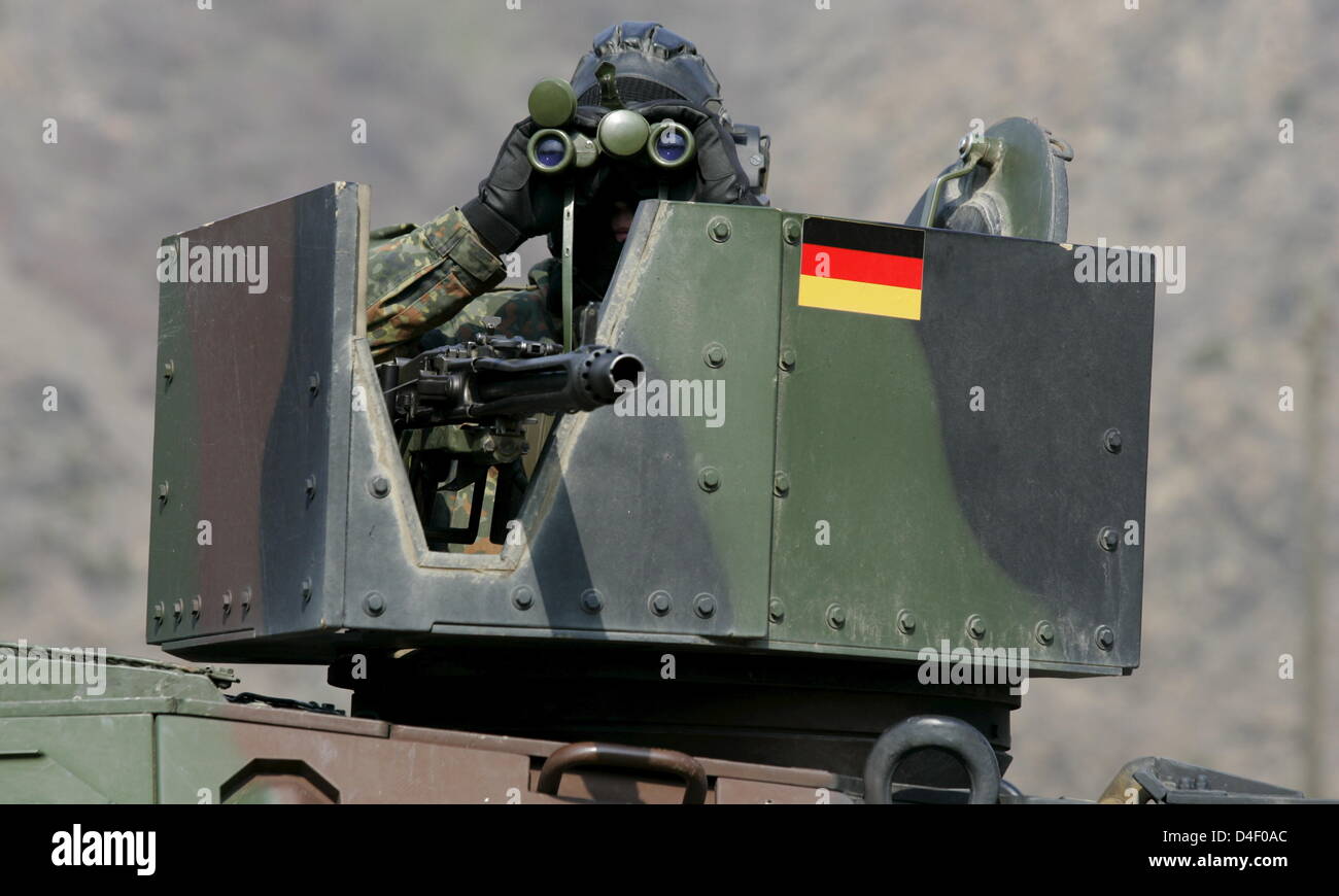 A soldier of the German Bundeswehr surveils the street from an armoured ...