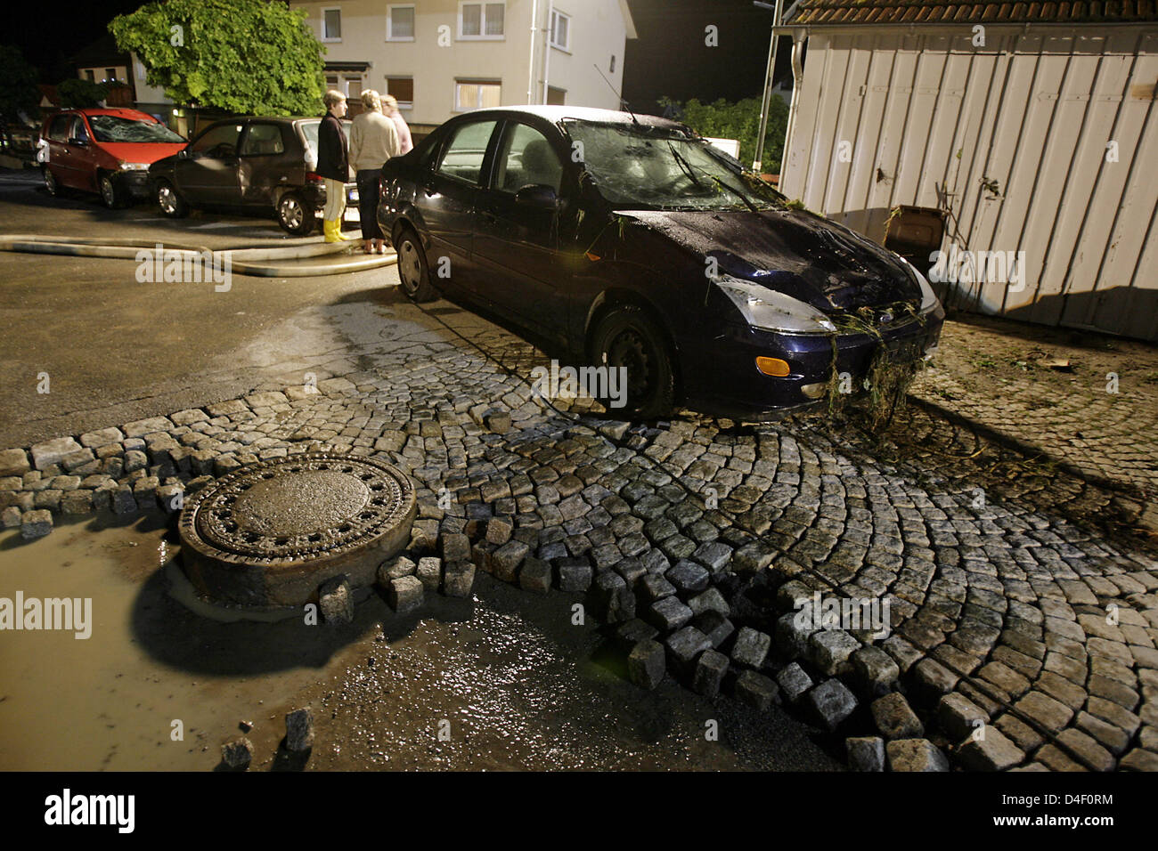 A car stands hit on an eroded street in Jungingen, Germany, 03 June ...
