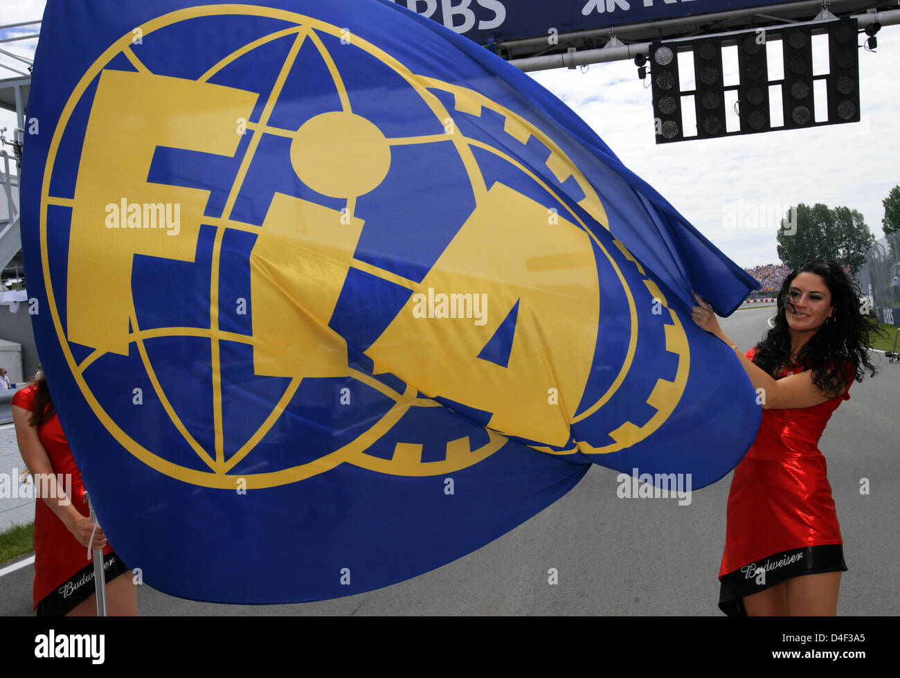 A grid girl holds the FIA flag against the wind on the starting grid ...