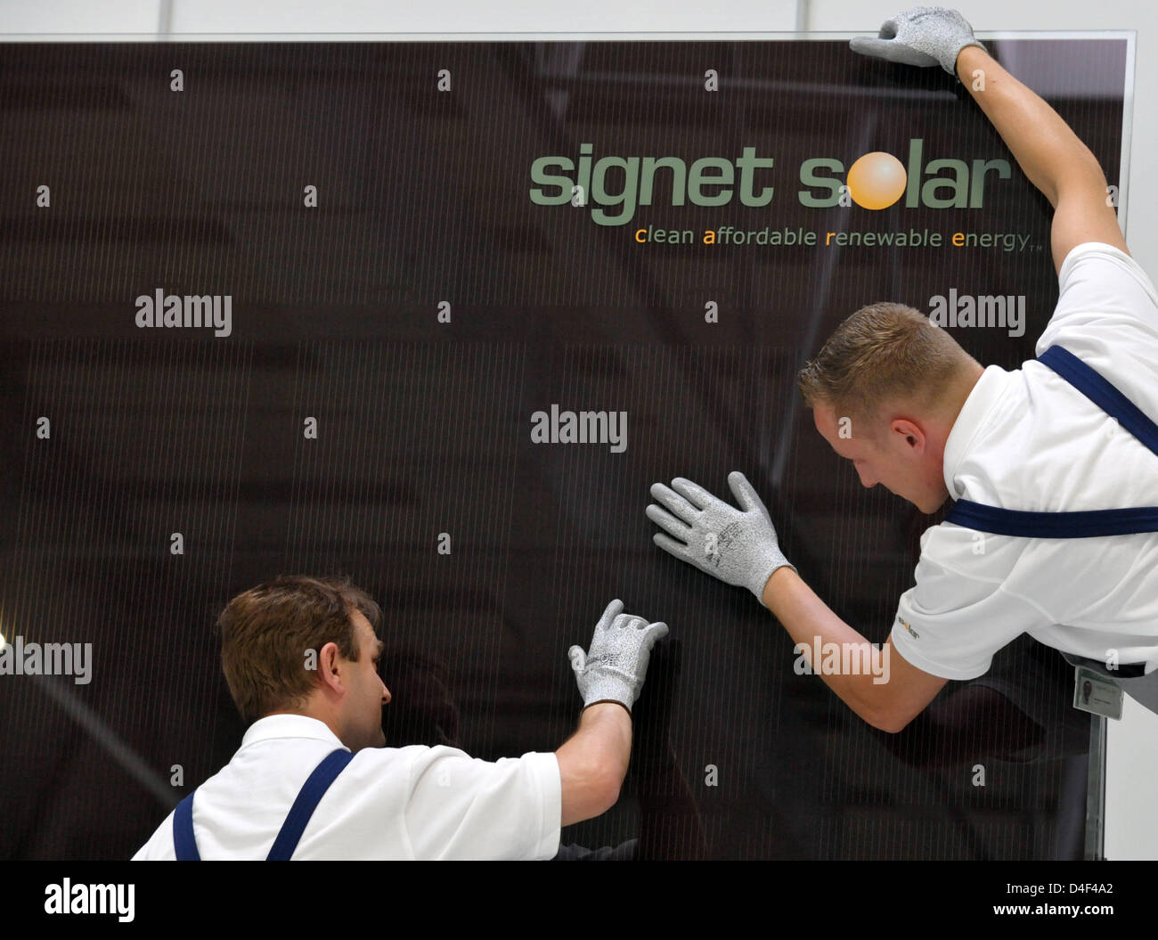 Two members of staff of solar panel producer Signet Solar check a panel ...