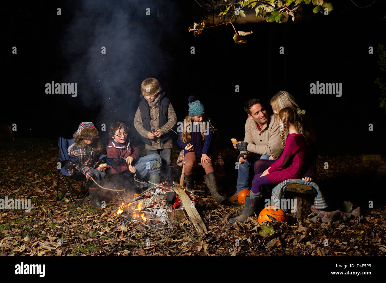 Family eating around campfire at night Stock Photo - Alamy