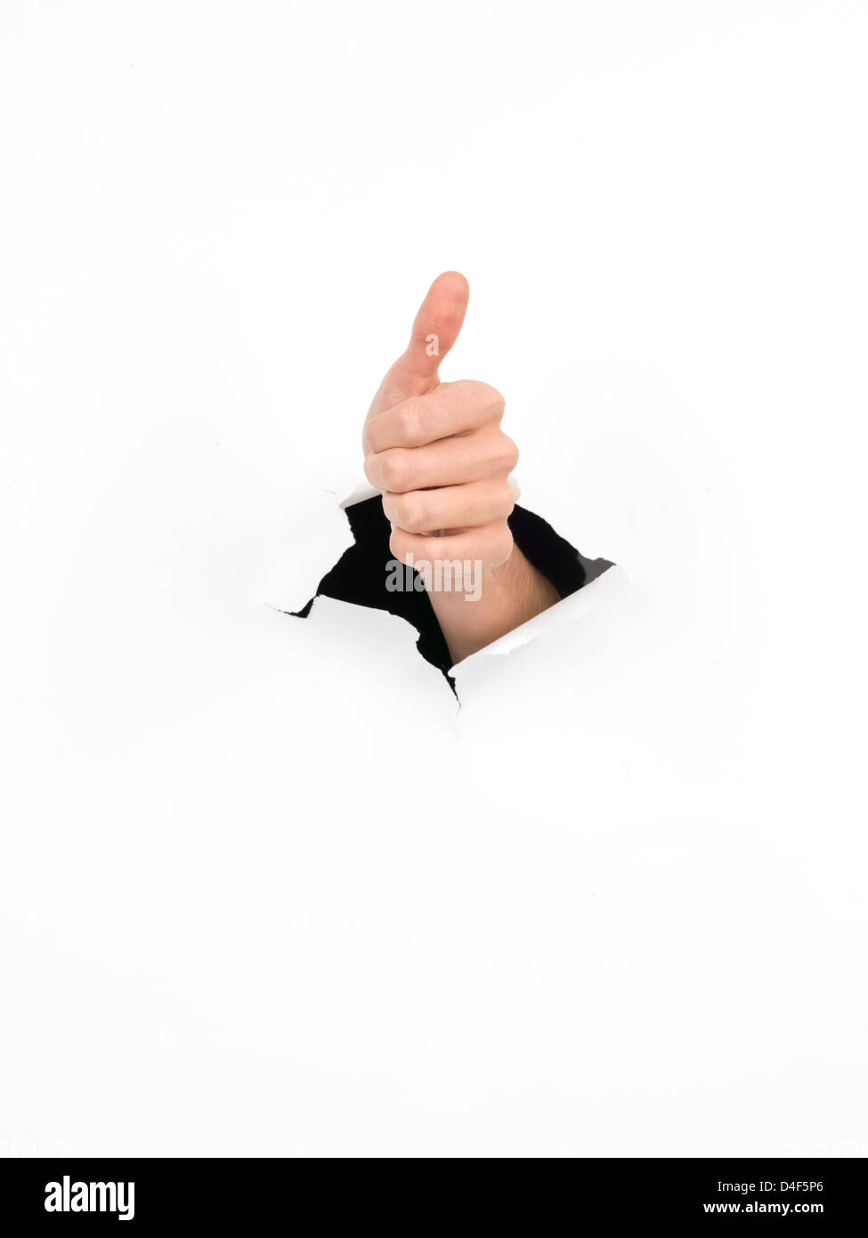 hand through a hole in a white paper with thumb up gesture, isolated ...