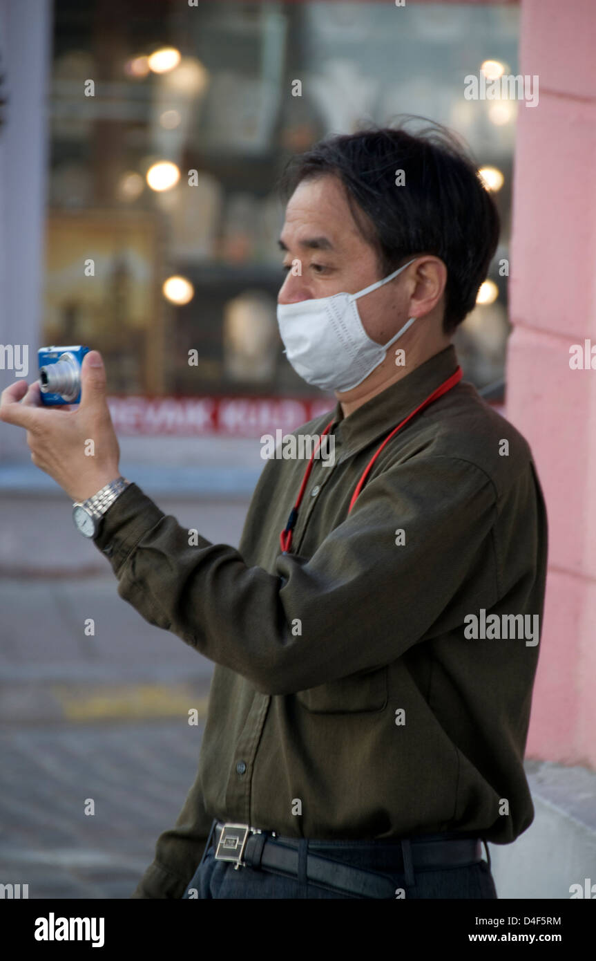 A face-masked Chinese tourist using his camera in Pikk, Tallinn Old ...