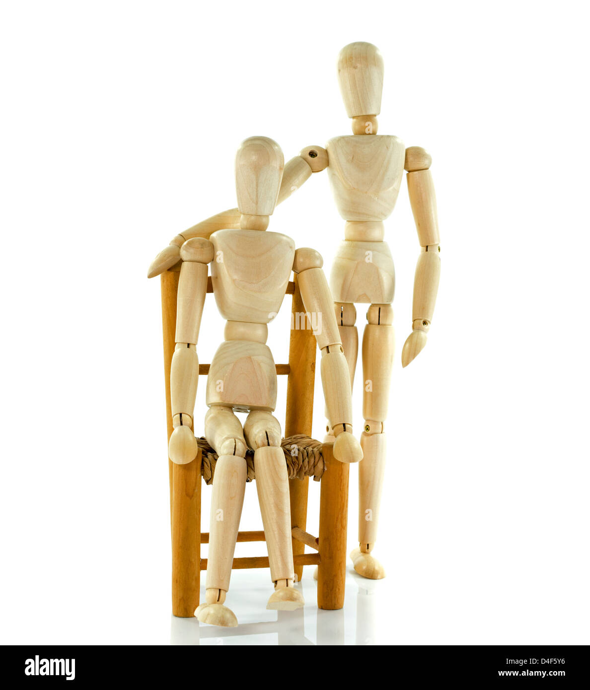 one wooden puppet giving care to other sitting model Stock Photo - Alamy