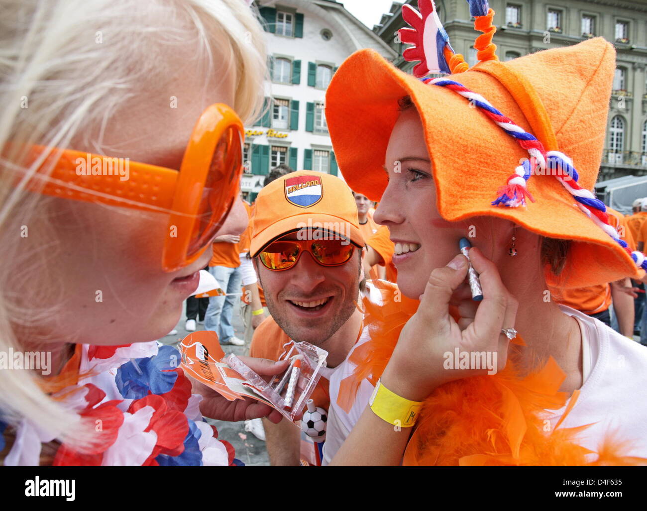 Supporter of Dutch soccer team paint colors on their skin in downtown ...