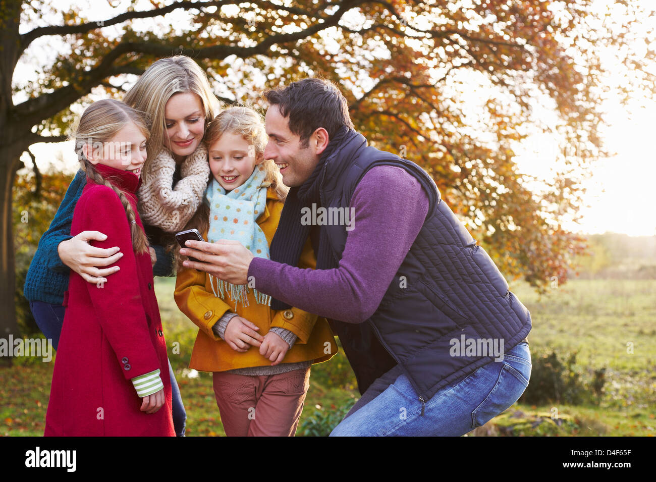 Family using cell phone together outdoors Stock Photo - Alamy