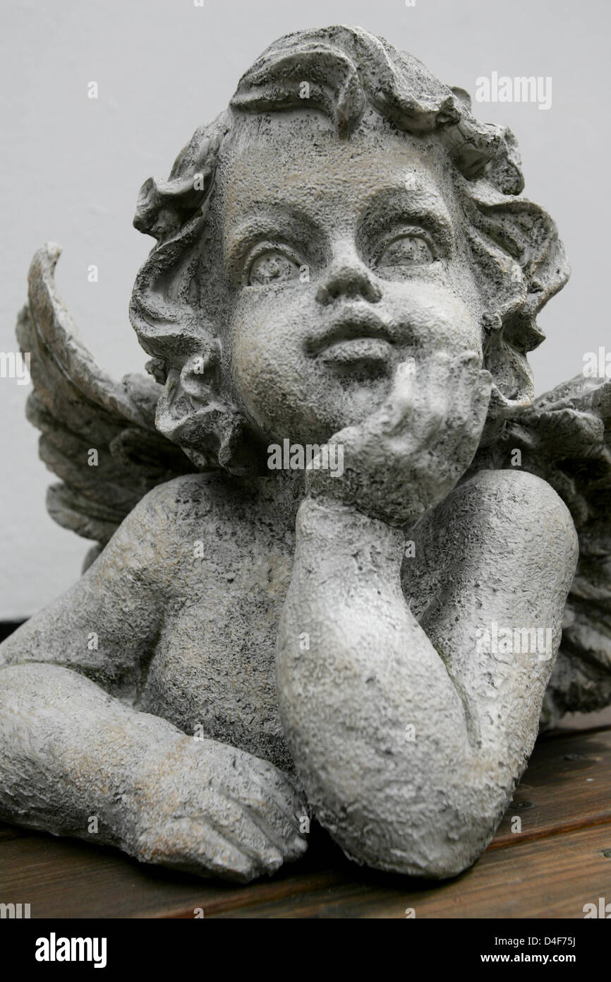 A stone sculpture resembling an angel with its chin resting on its hand ...