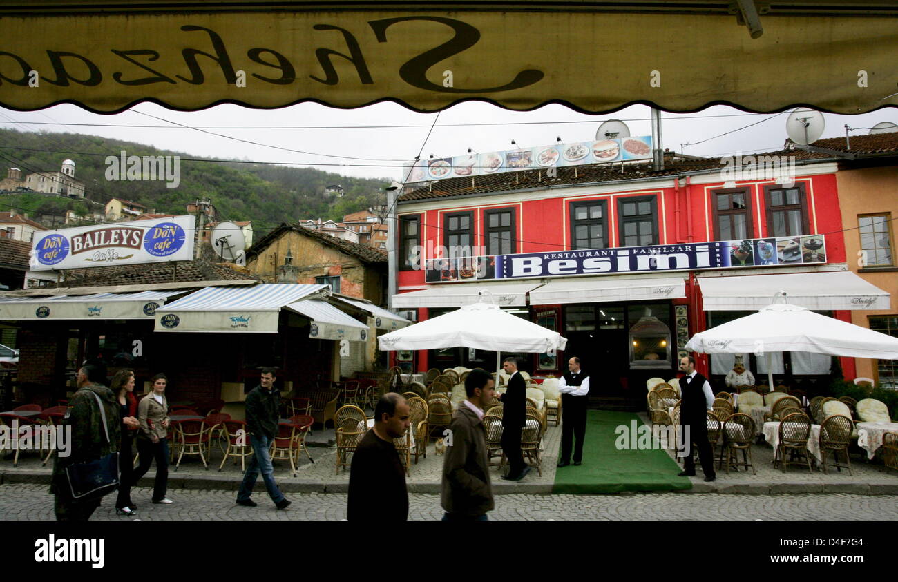 People chat on a road in front of a pavement cafe in Prizren, Kosovo ...