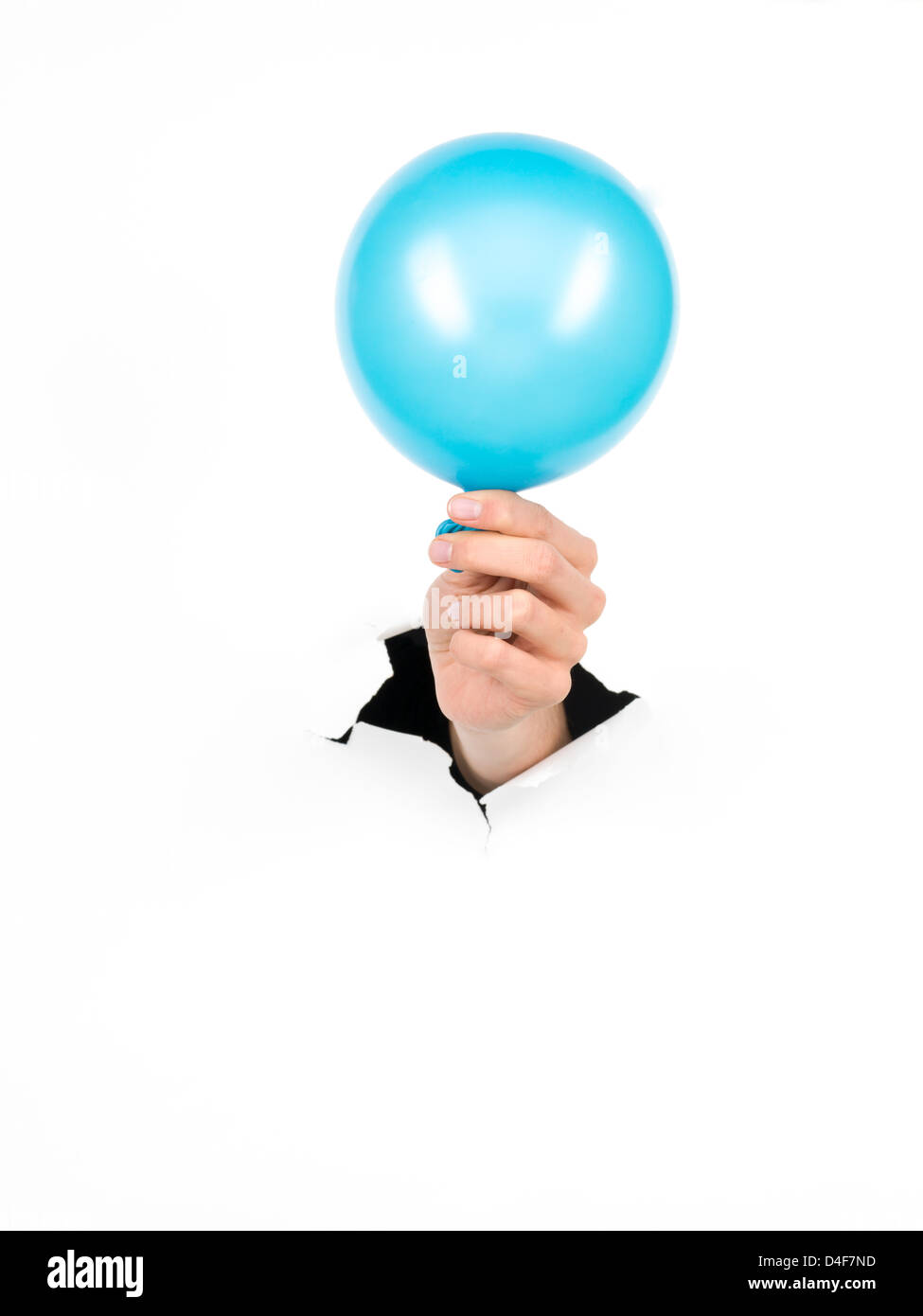close-up of female hand holding a balloon through a torn white paper ...