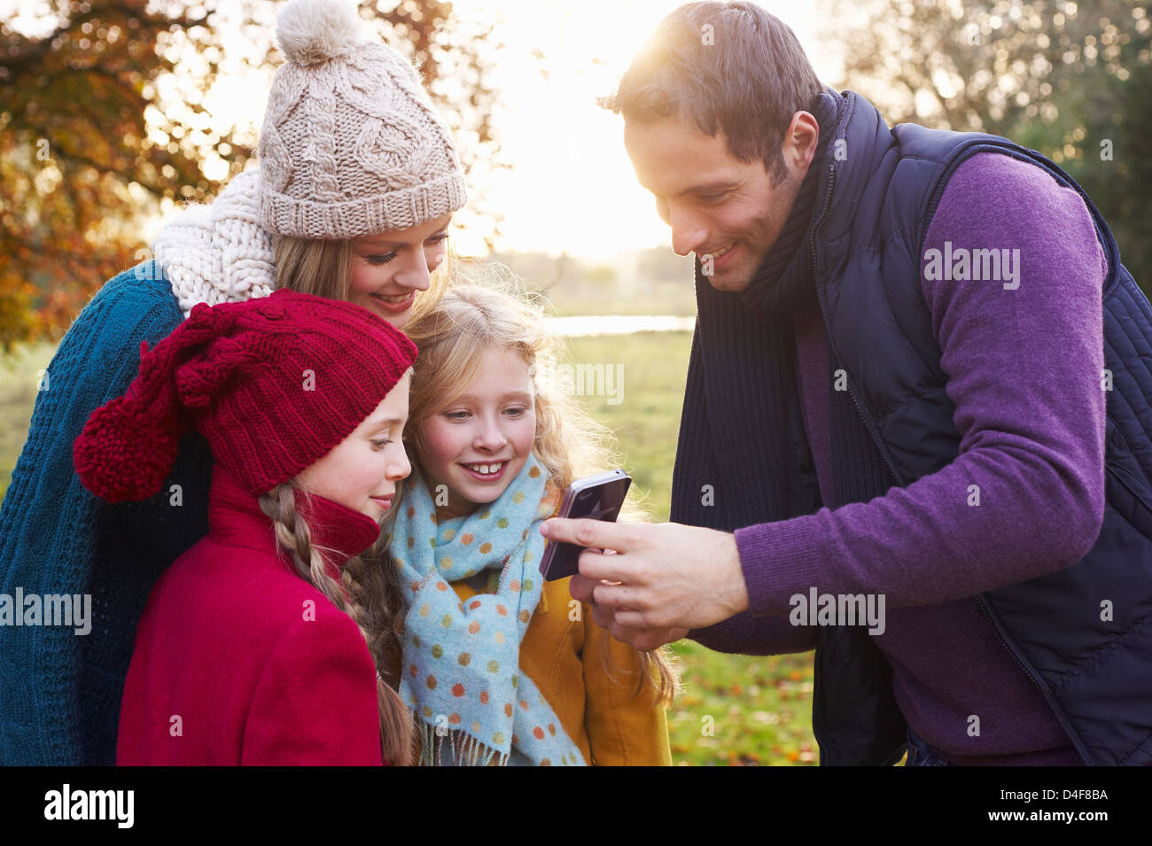 Family using cell phone together outdoors Stock Photo - Alamy