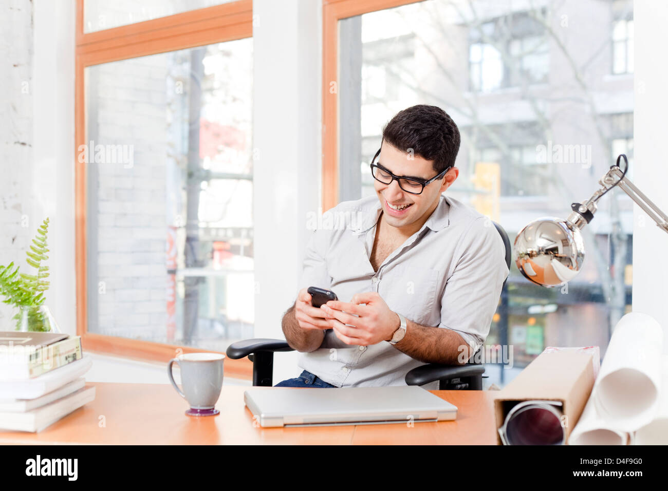 Businessman using cell phone in office Stock Photo - Alamy