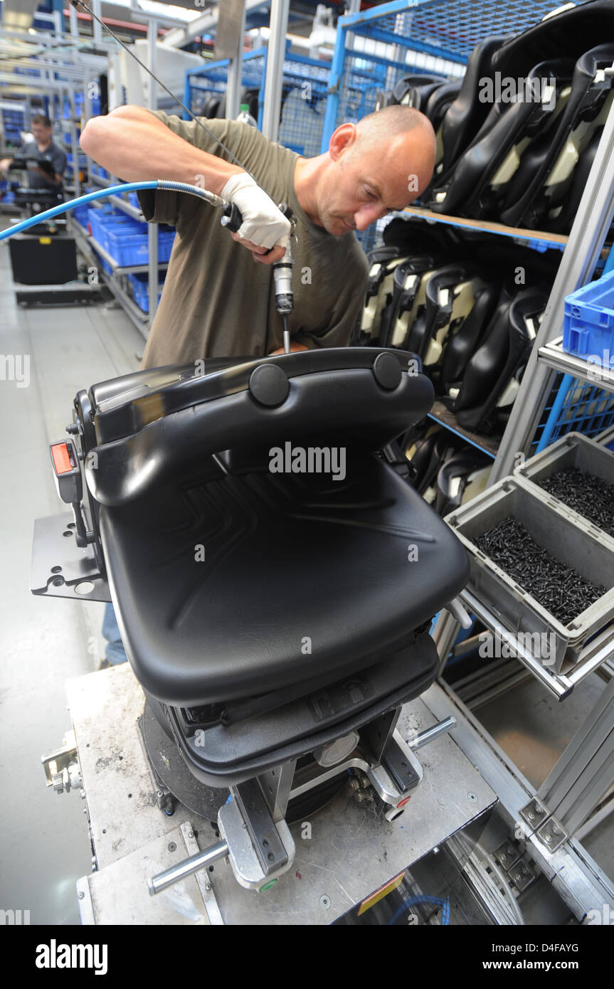 An employee of car supplier Grammer assembles a vehicle seat at the ...