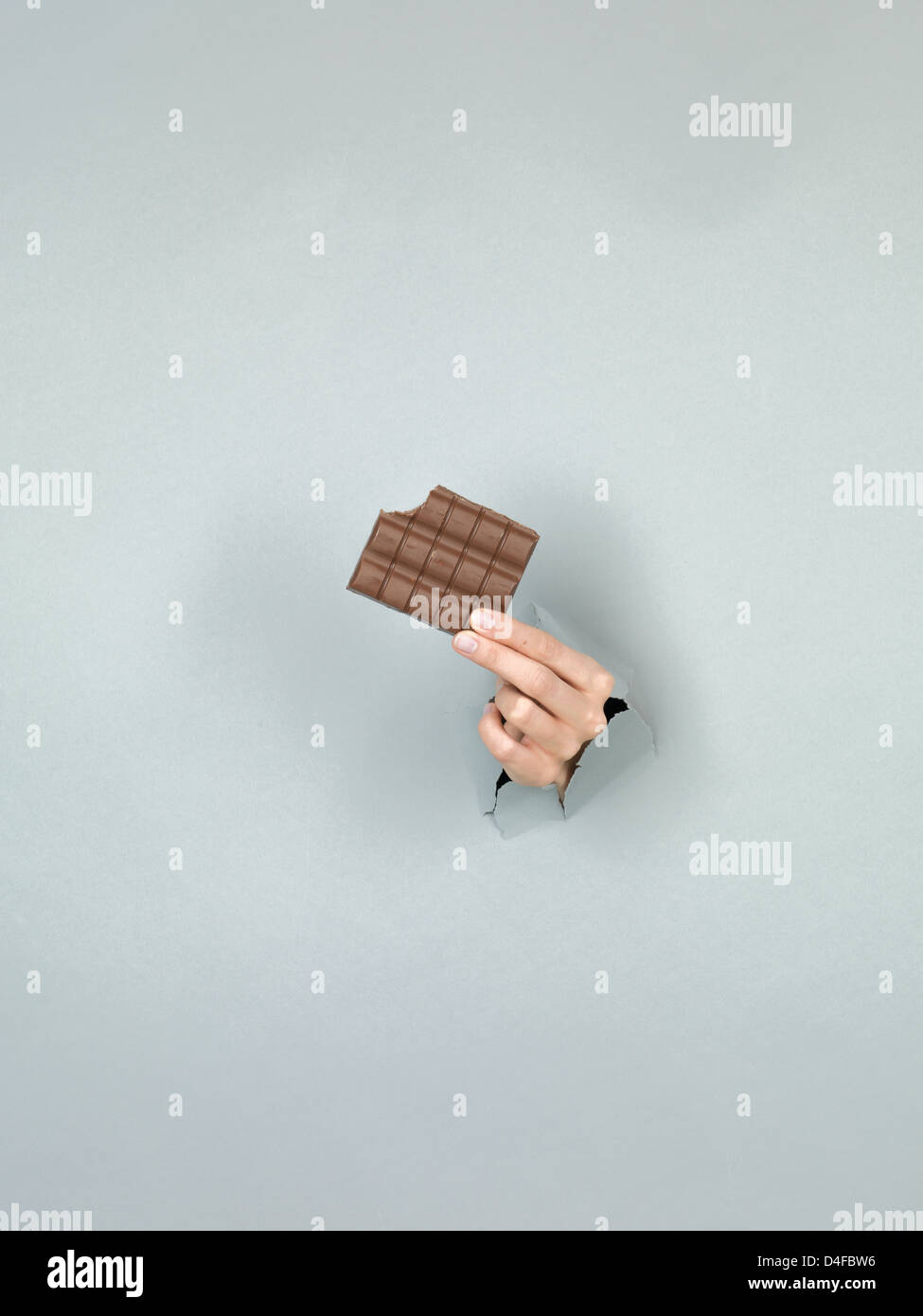 close-up of female hand holding a bar of bitten chocolate through a ...