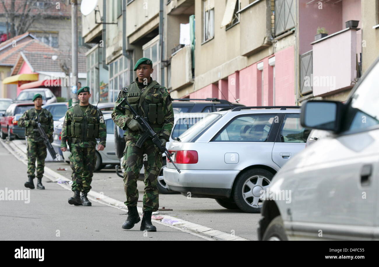 Three armed Portuguese soldiers patrol the streets of Mitrovica, Kosovo ...
