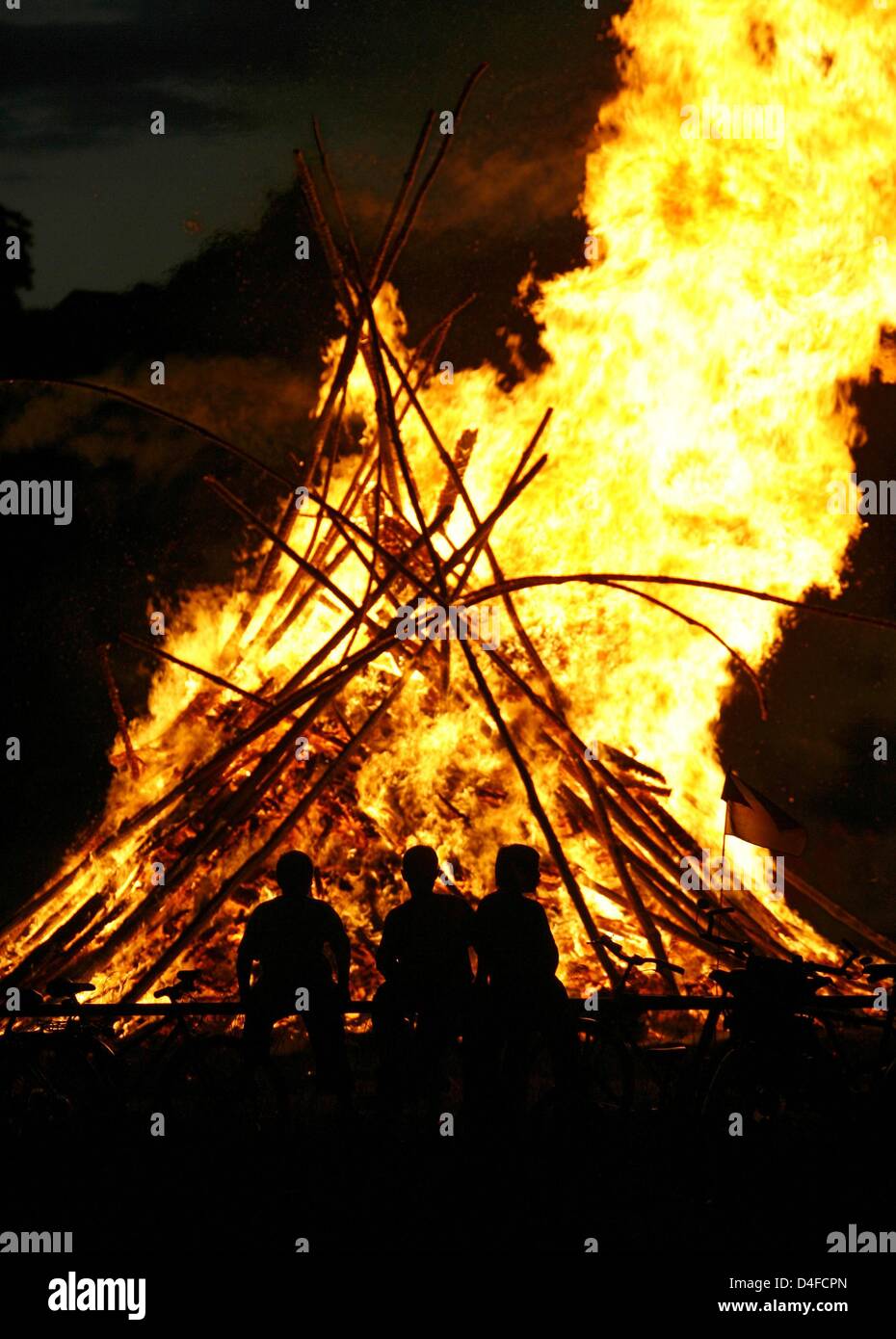 Three lads watch the Midsummer Night bonfire in Dettelbach, Germany, 28 ...