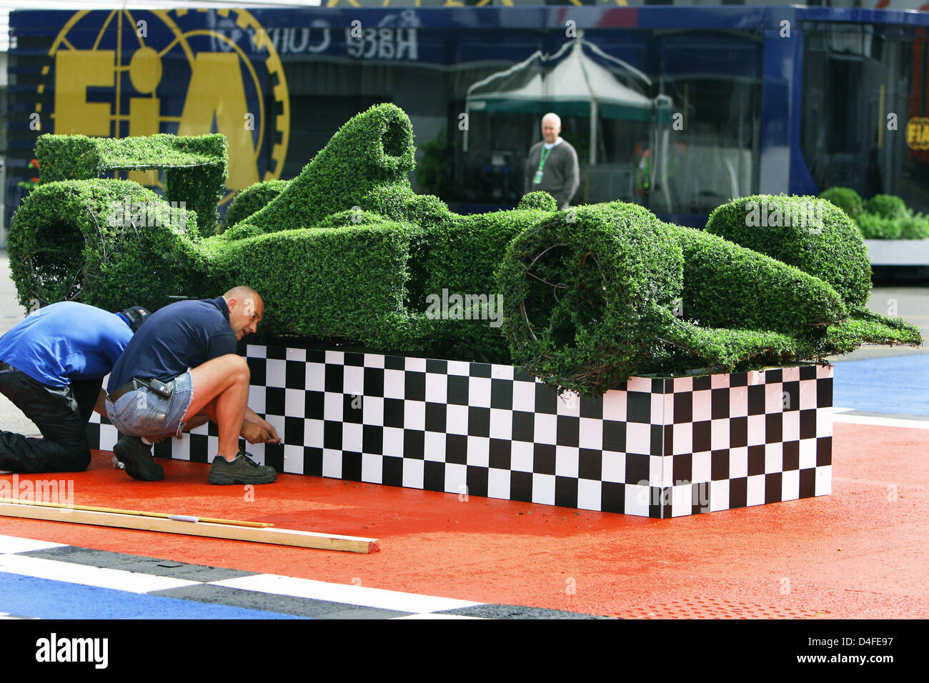 Workers set up a Formula 1-Car shaped hedge at the Silverstone race ...