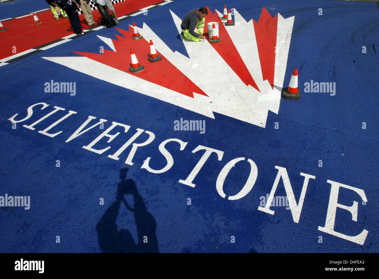 A worker paints the Silverstone logo on the ground at the paddock of ...