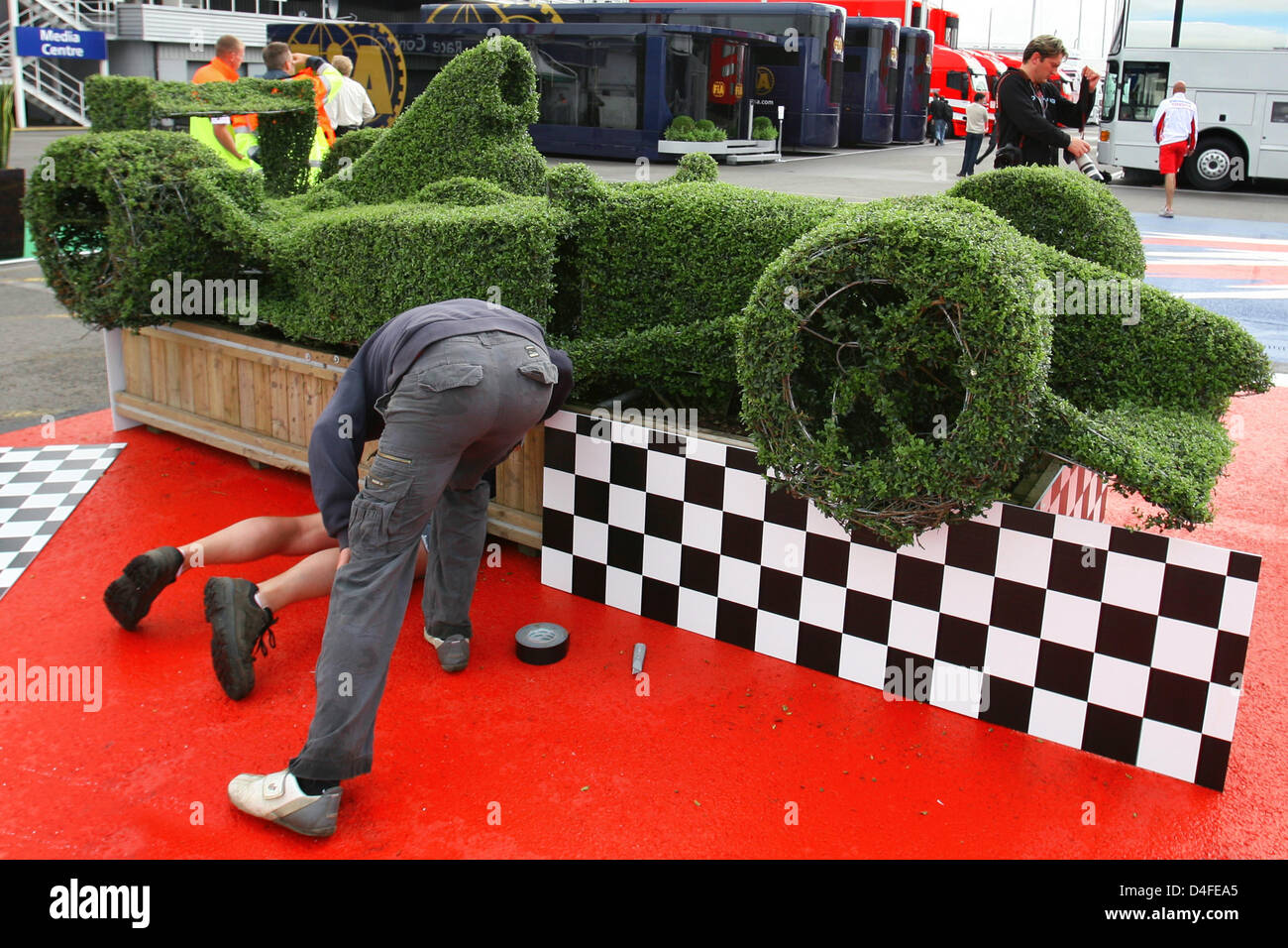 Workers set up a Formula 1-Car shaped hedge at the Silverstone race ...