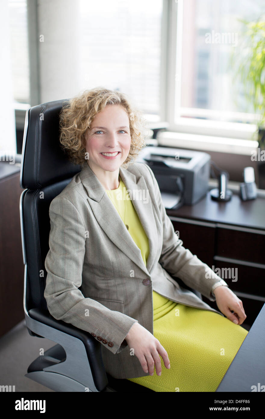 Businesswoman smiling at desk Stock Photo - Alamy