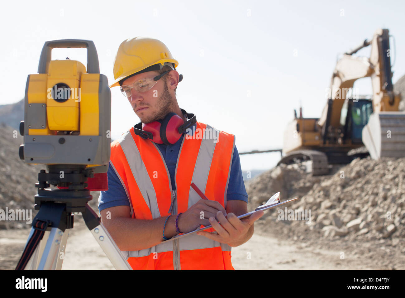 Worker using leveling equipment in quarry Stock Photo - Alamy