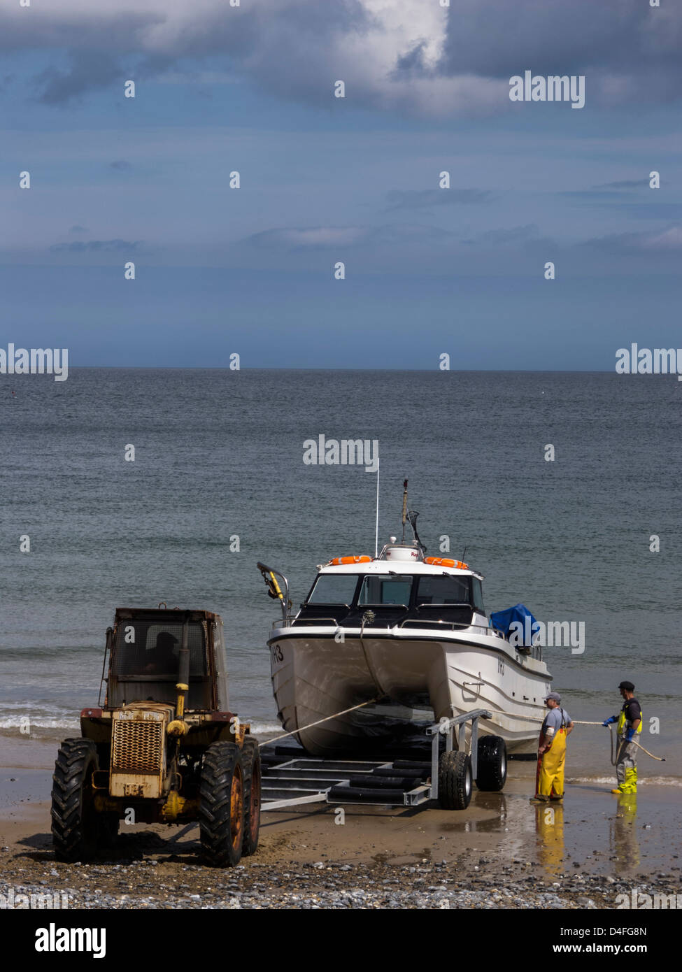 Large crab/fishing boat being pulled onto trailer by a tractor with two ...