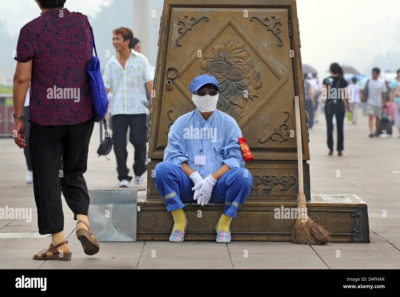 A women in cleaning clothes is sitting in the streets of Beijing, China ...