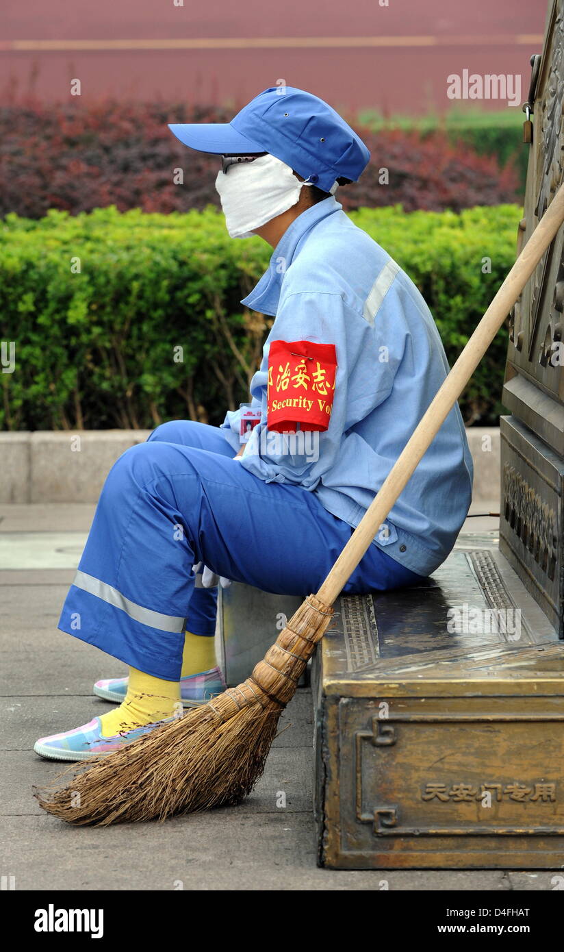 A women in cleaning clothes is sitting in the streets of Beijing, China ...