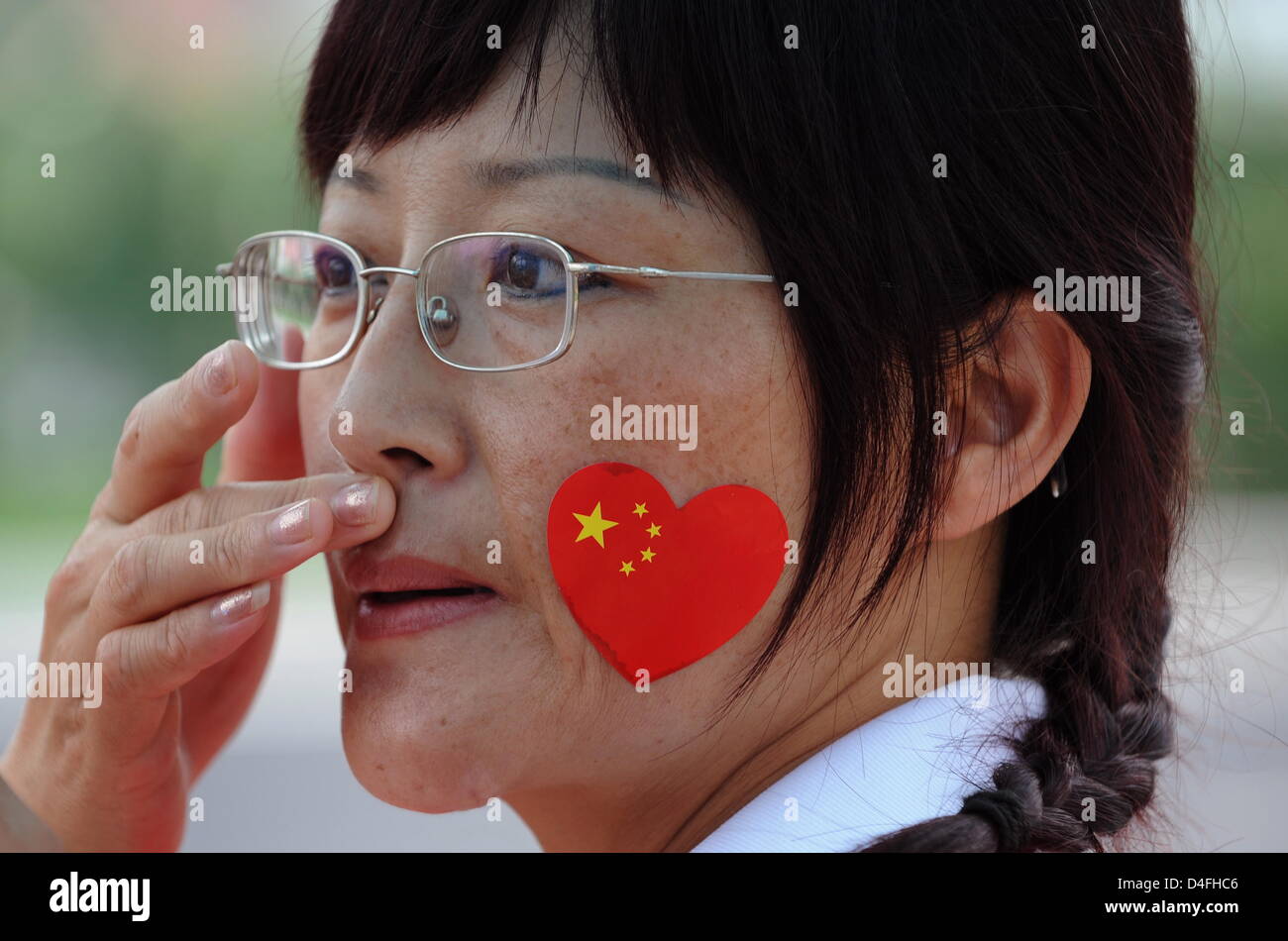 A women has the Chinese flag painted on her cheek in Beijing, China, 07 ...