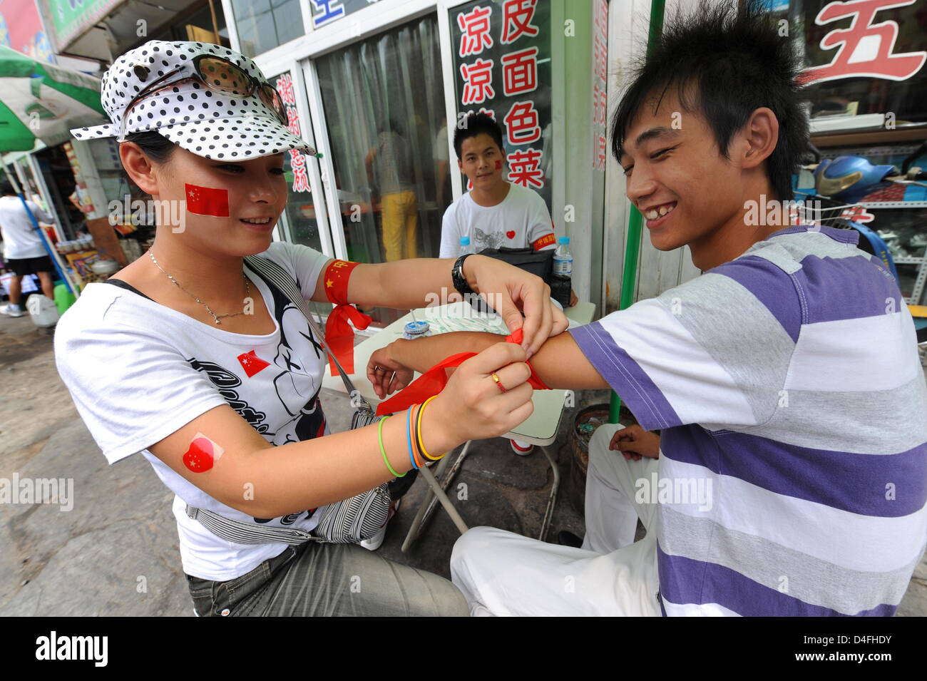 A chinese girl decorates a boy in the streets of Beijing, China, 07 ...