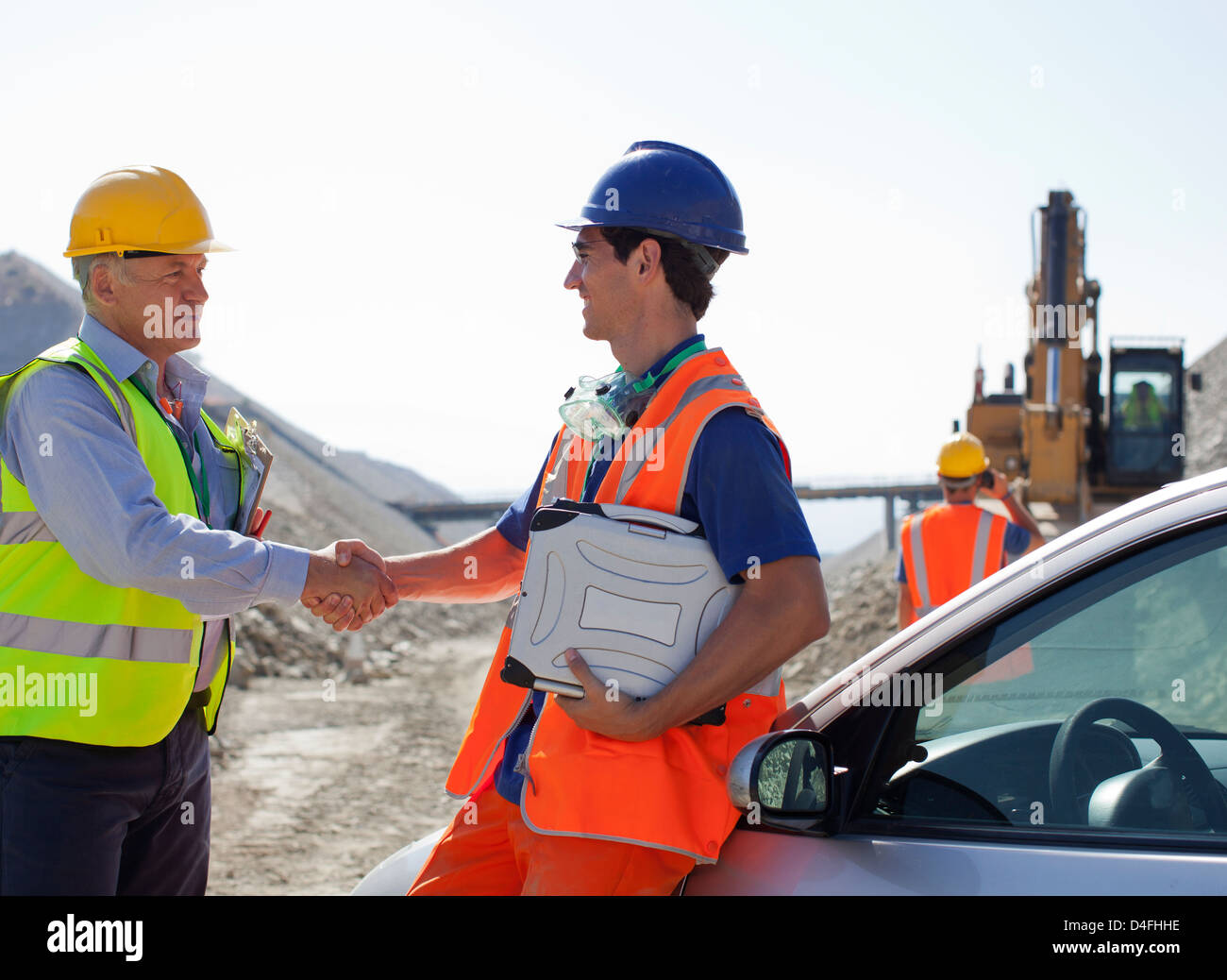 Worker and businessman shaking hands in quarry Stock Photo - Alamy