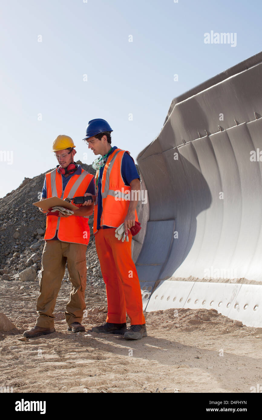 Workers talking by machinery in quarry Stock Photo - Alamy