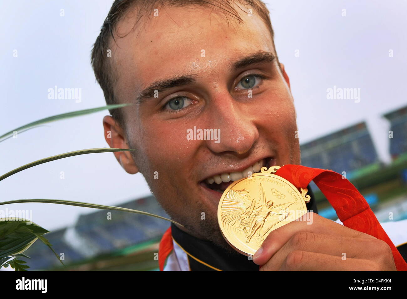 German Alexander Grimm bites his goldmedal on the podium after winning ...