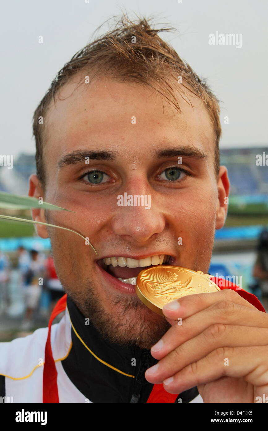 German Alexander Grimm bites his goldmedal on the podium after winning ...