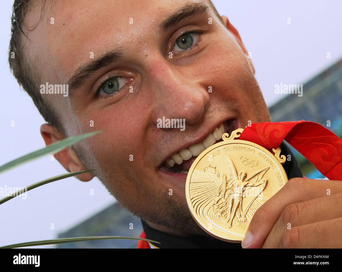 German Alexander Grimm bites his goldmedal on the podium after winning ...