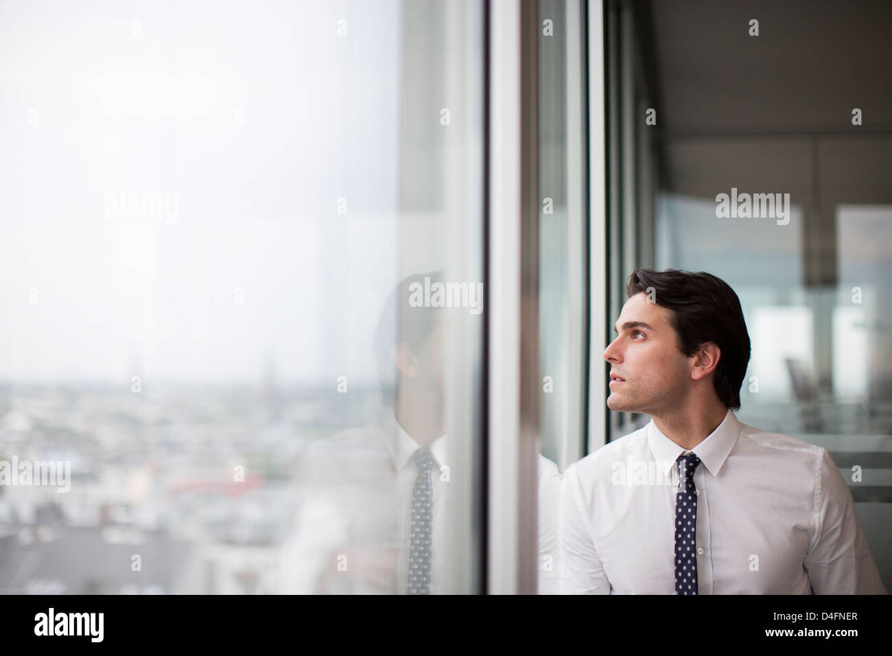 Businessman looking out office window Stock Photo - Alamy