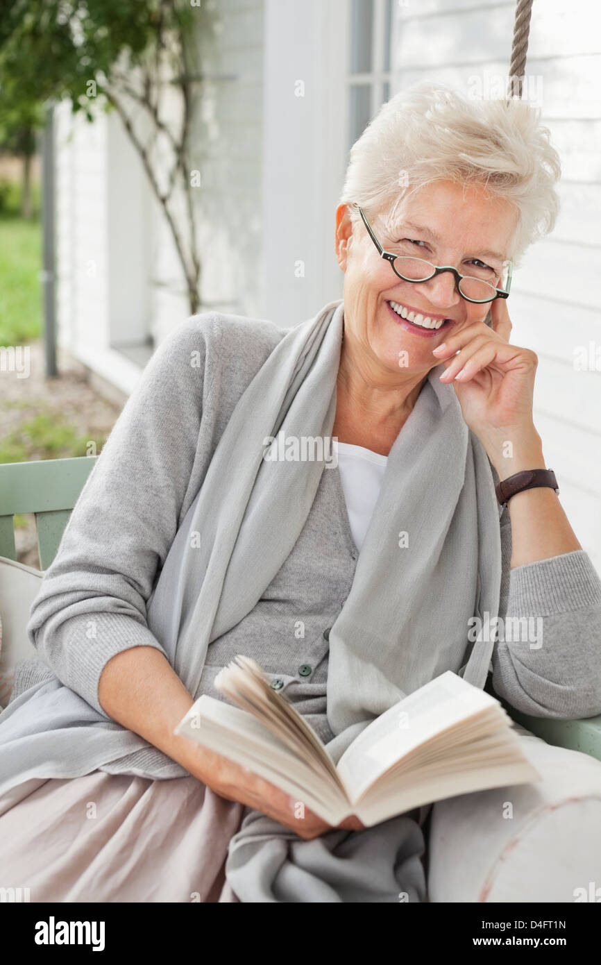 Woman reading book on porch swing Stock Photo - Alamy