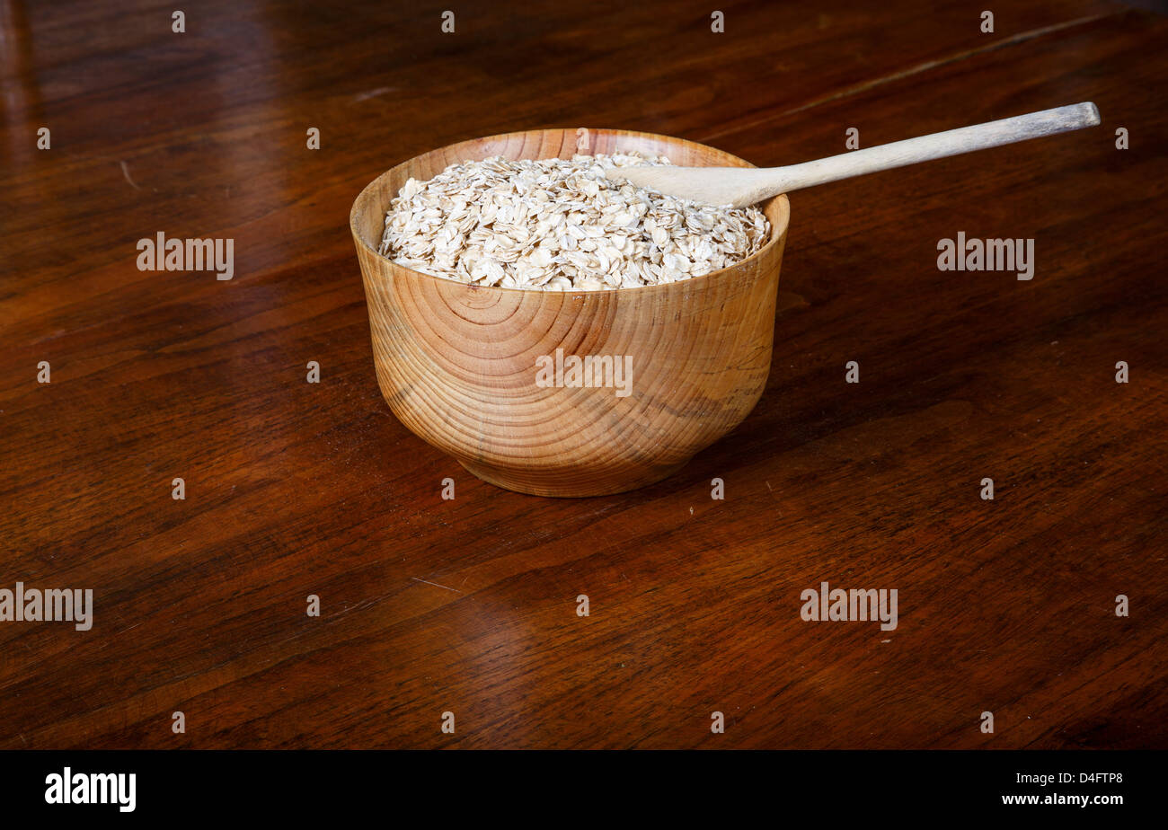 A bowl of fresh oatmeal ready to cook in a wood bowl with wood spoon on ...